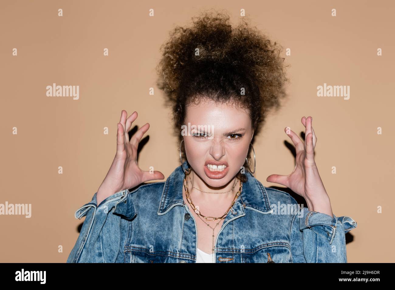 Angry model in denim jacket looking at camera on beige background Stock ...