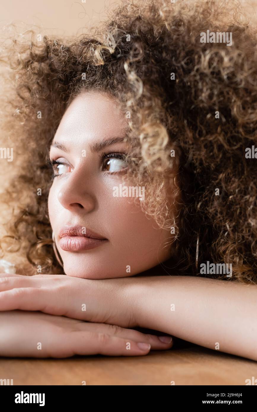 Young curly model looking away isolated on beige Stock Photo - Alamy