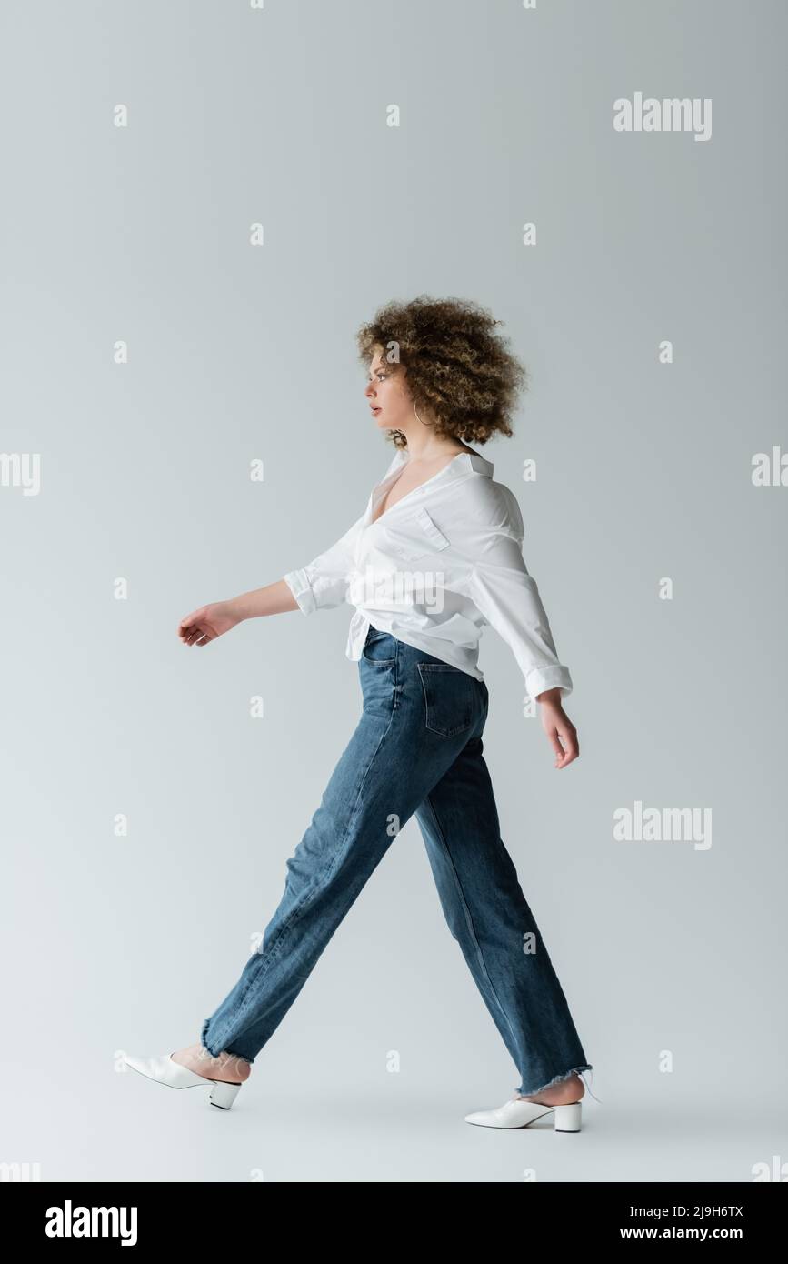 Side view of stylish woman walking on white background Stock Photo - Alamy