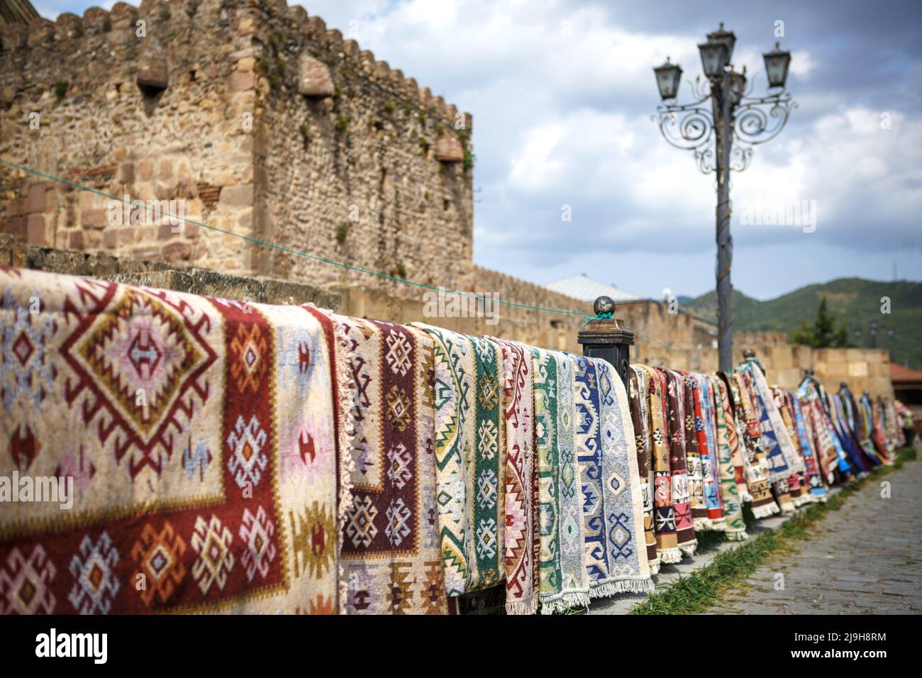 Handmade carpets hang on a stone wall - tourist souvenirs from Georgia ...