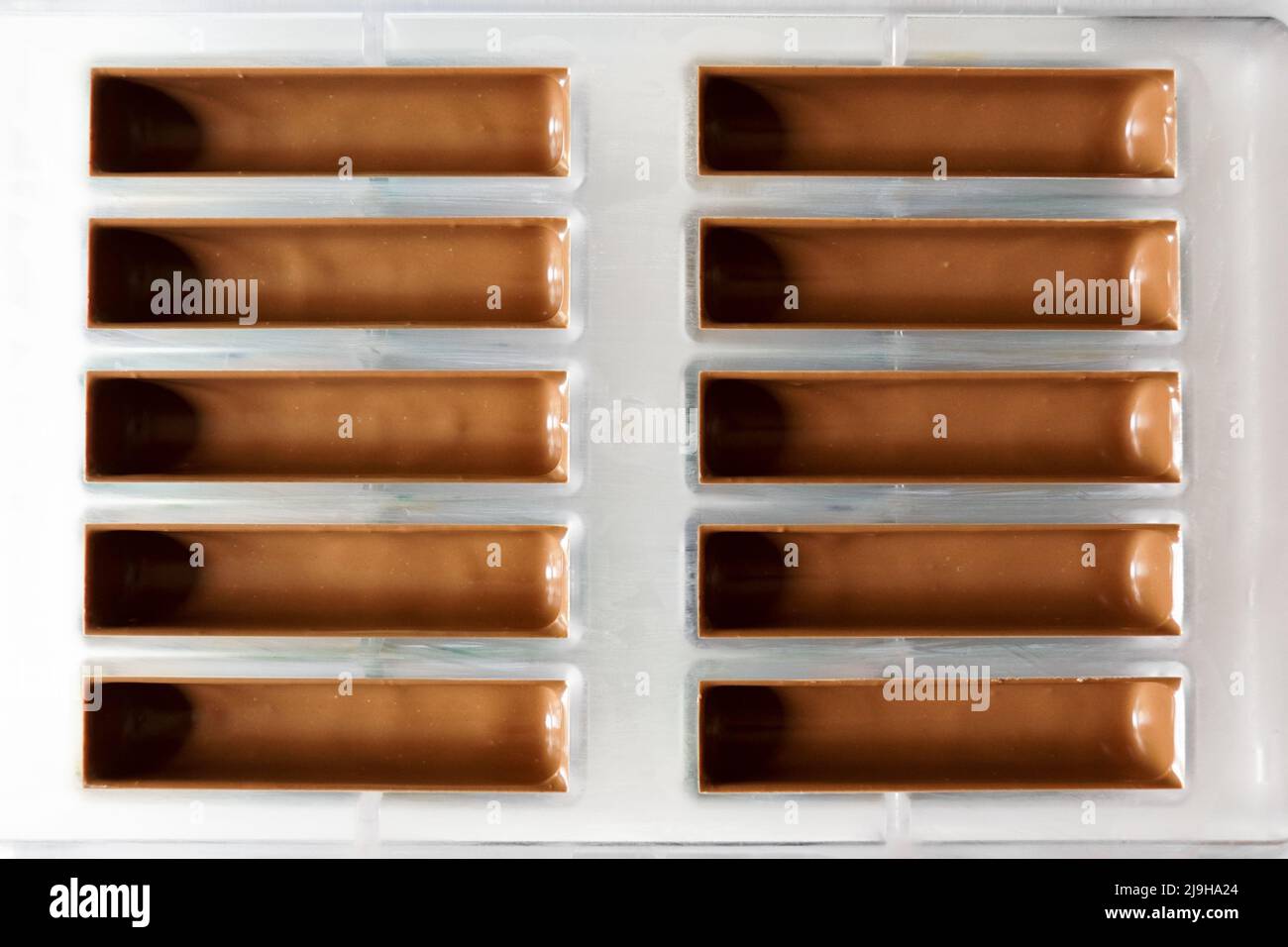 Chocolate poured into plastic mold. Frame for filling chocolate bars ...