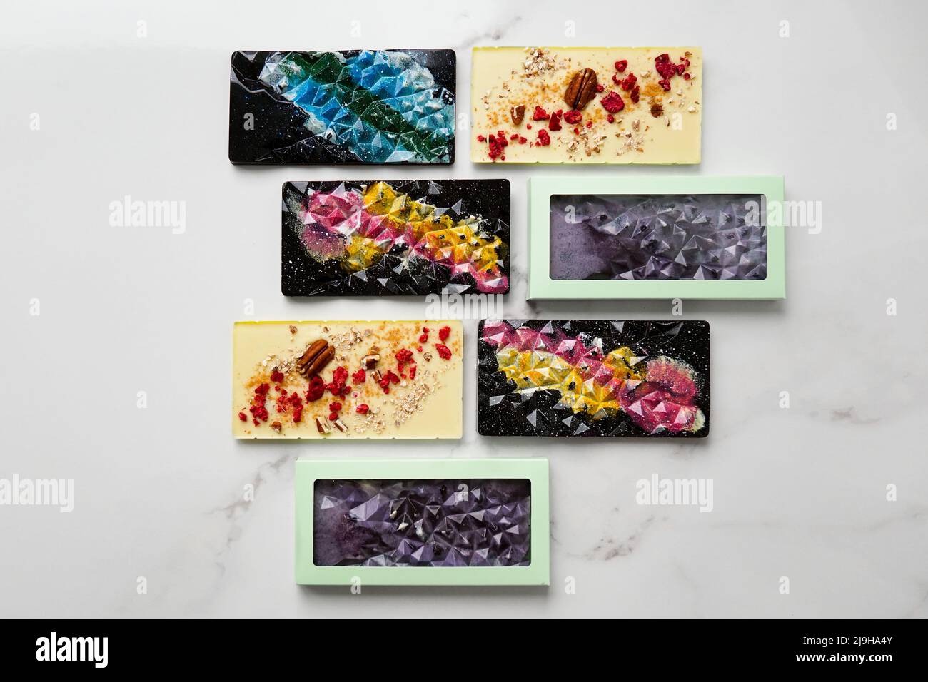 Hand-made bars of colorful chocolate on a light marble background ...