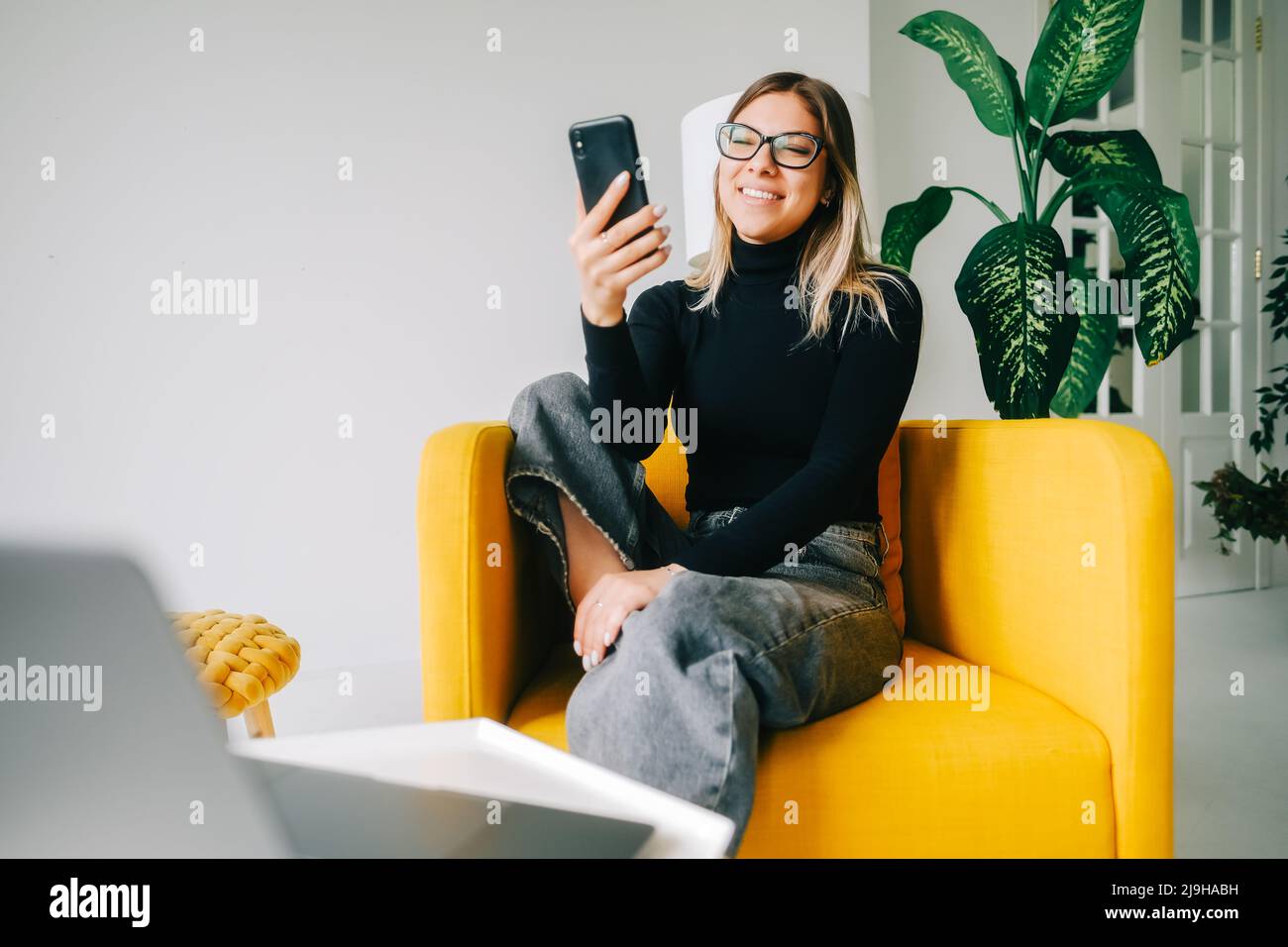 Young cheerful attractive woman in eyeglasses using mobile phone at ...