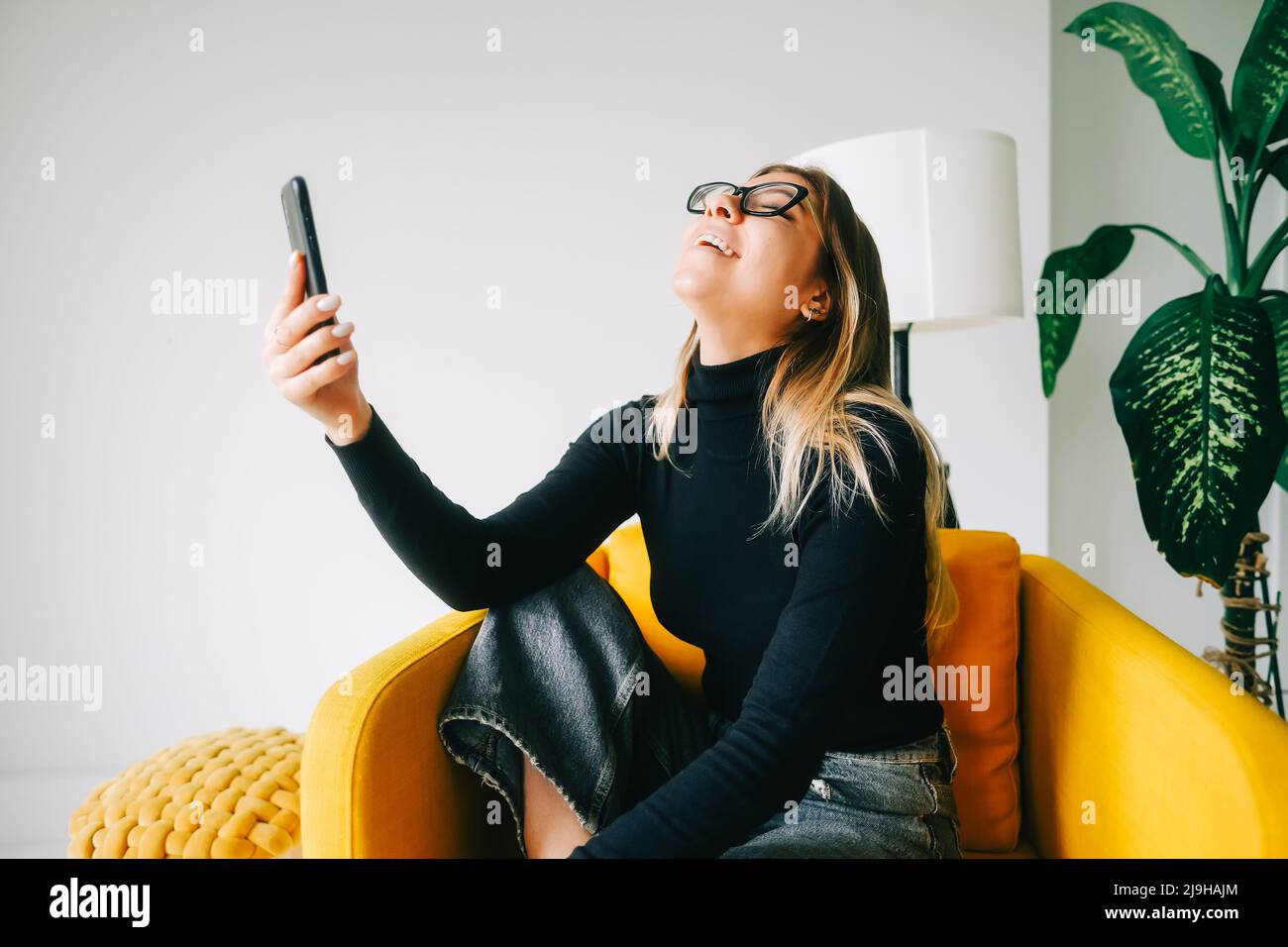 Young cheerful attractive woman in eyeglasses using mobile phone at ...