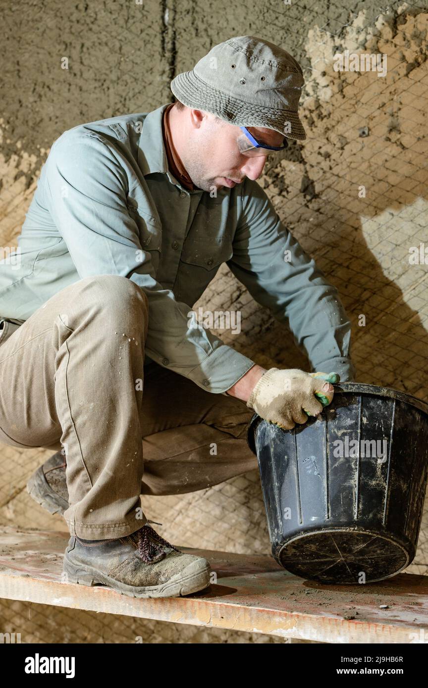 Black bucket with liquid mortar for the first layer of plaster for the ...