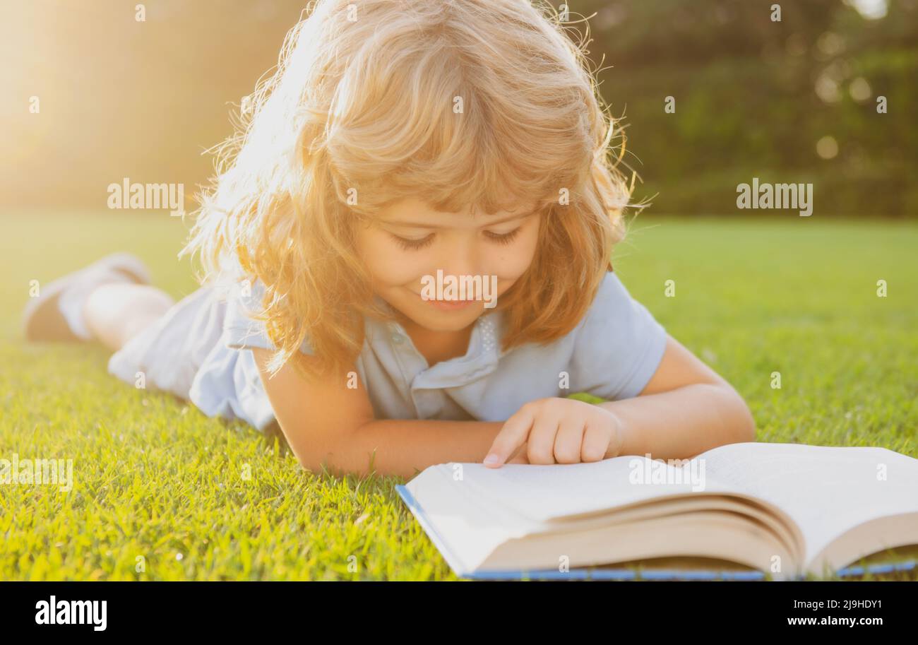 Beautiful child boy book on grass background. Kids reading book in park ...