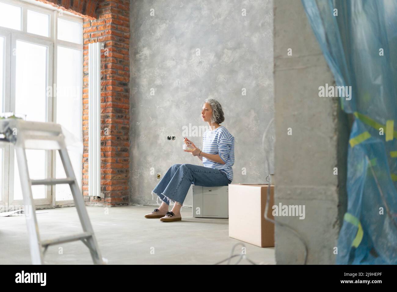 Woman taking lunch break sitting on box in front of wall Stock Photo ...