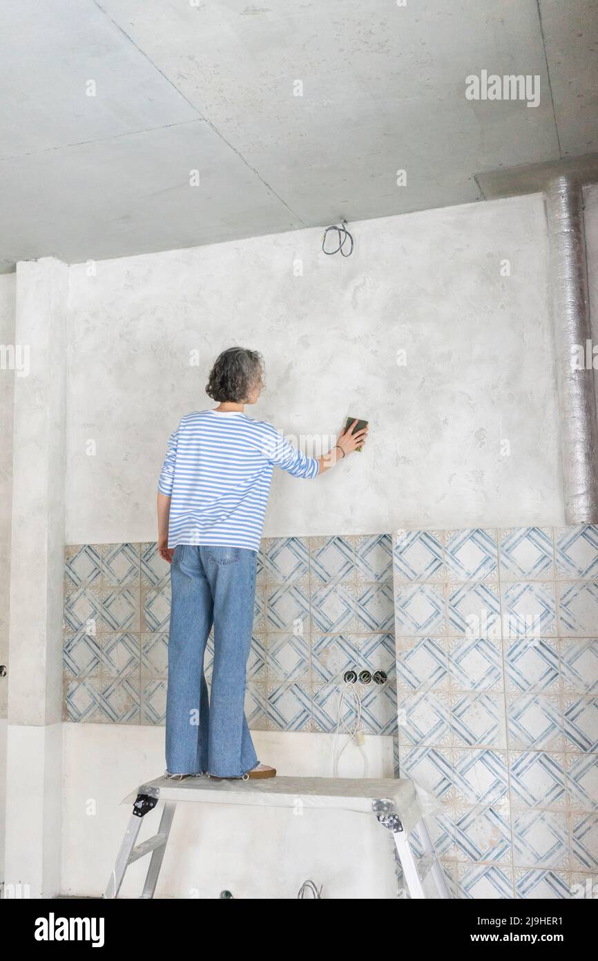 Woman standing on table scrubbing wall at new home Stock Photo - Alamy