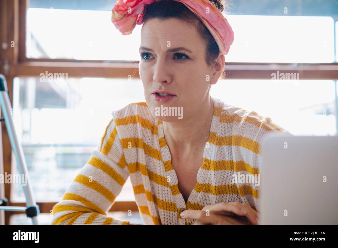 Angry woman wearing bandana sitting in front of window at home Stock ...