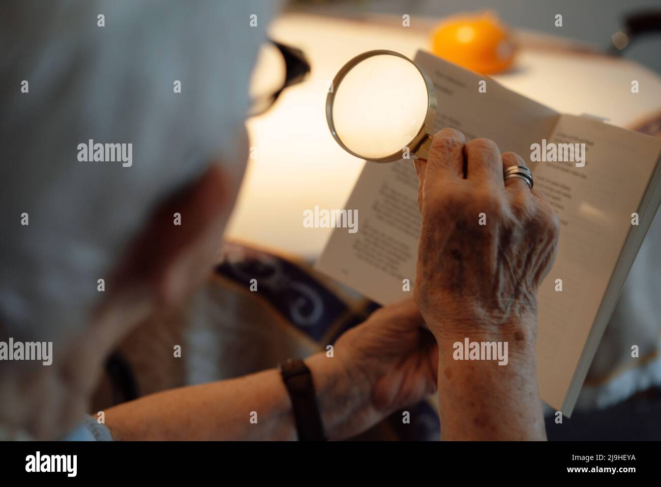Senior woman with magnifying glass reading book at home Stock Photo - Alamy