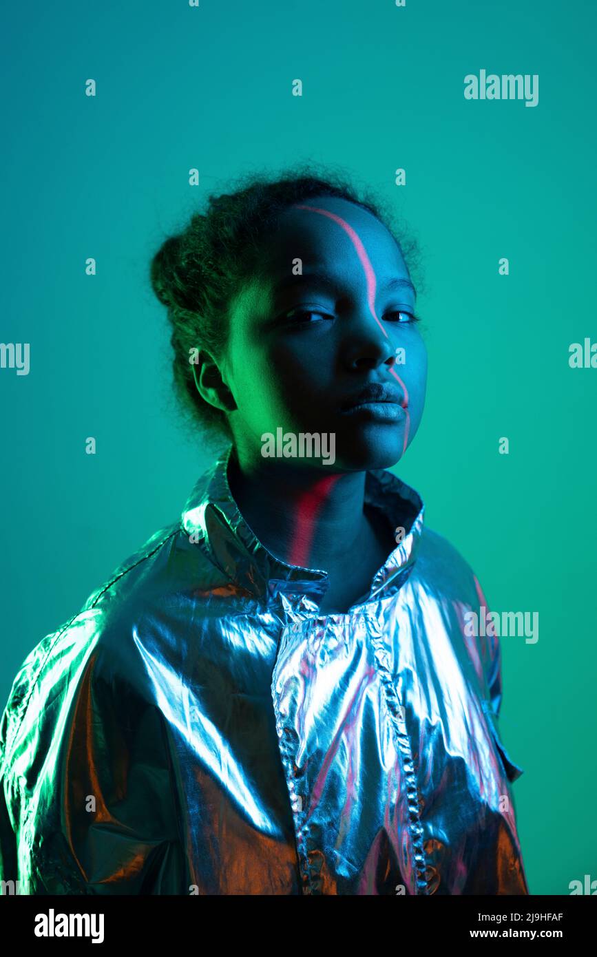 Laser light falling on young woman's face standing against green ...