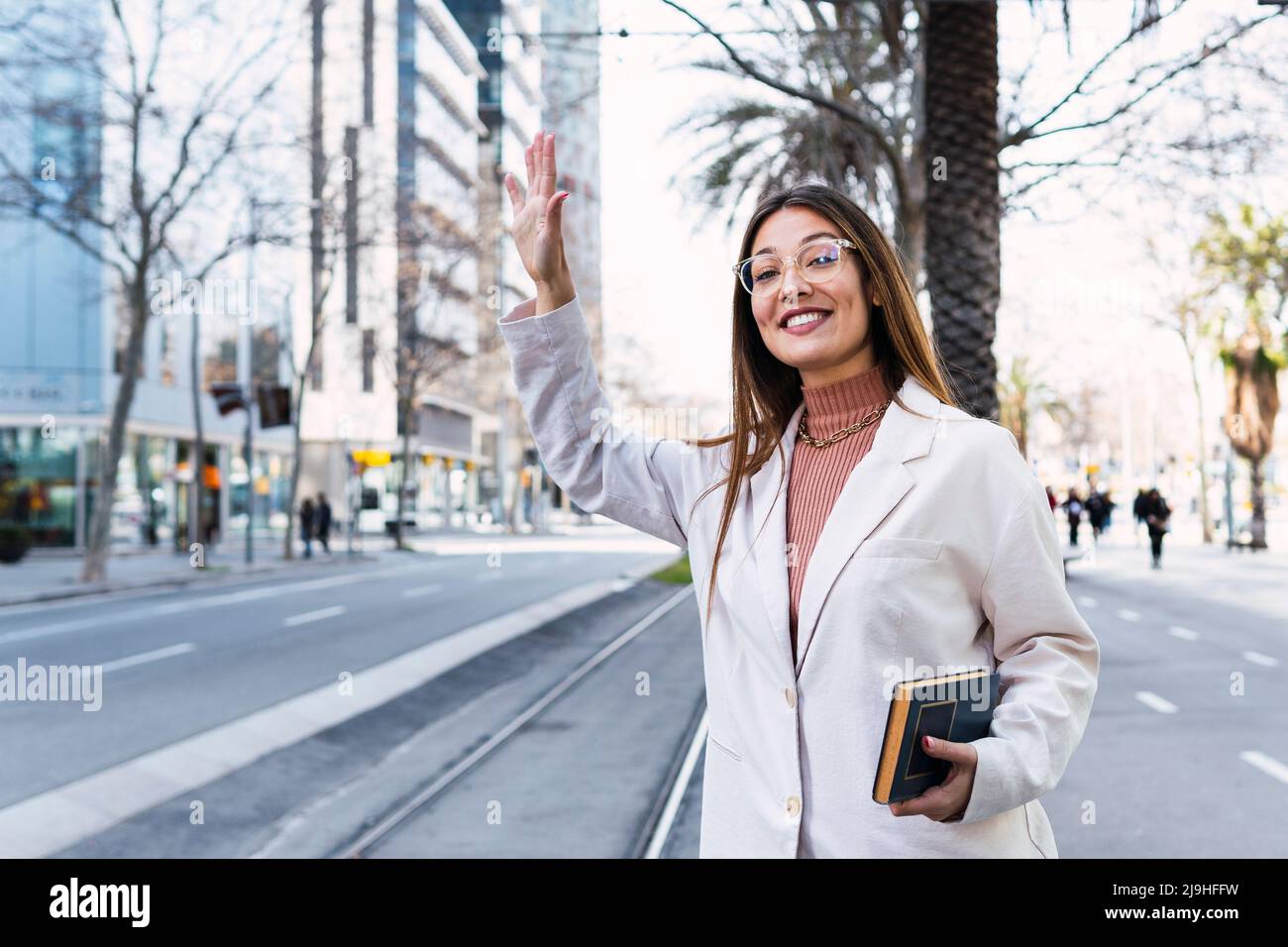 Happy woman hailing ride standing on city street Stock Photo - Alamy