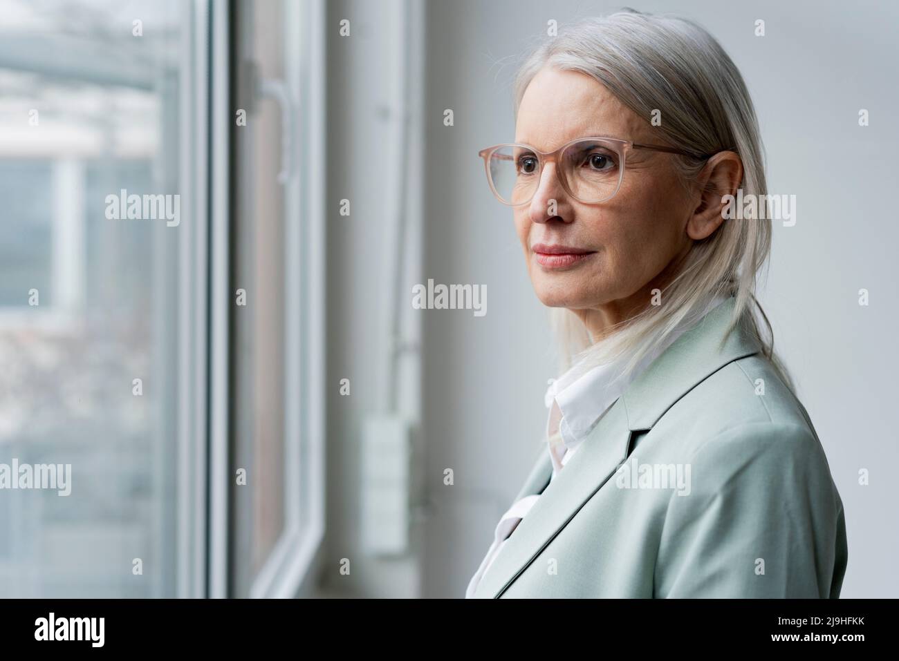 Contemplative businesswoman near window at office Stock Photo - Alamy