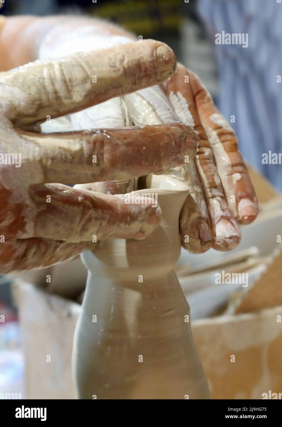 hand of the expert potter while he shapes a clay pot using pressure on ...