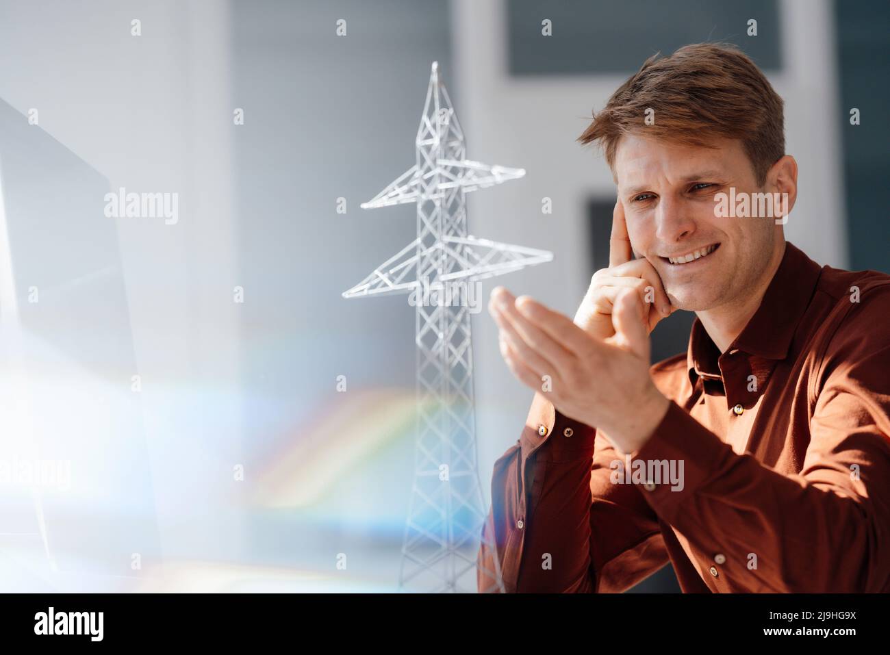 Smiling engineer analyzing at electricity pylon model in office Stock ...
