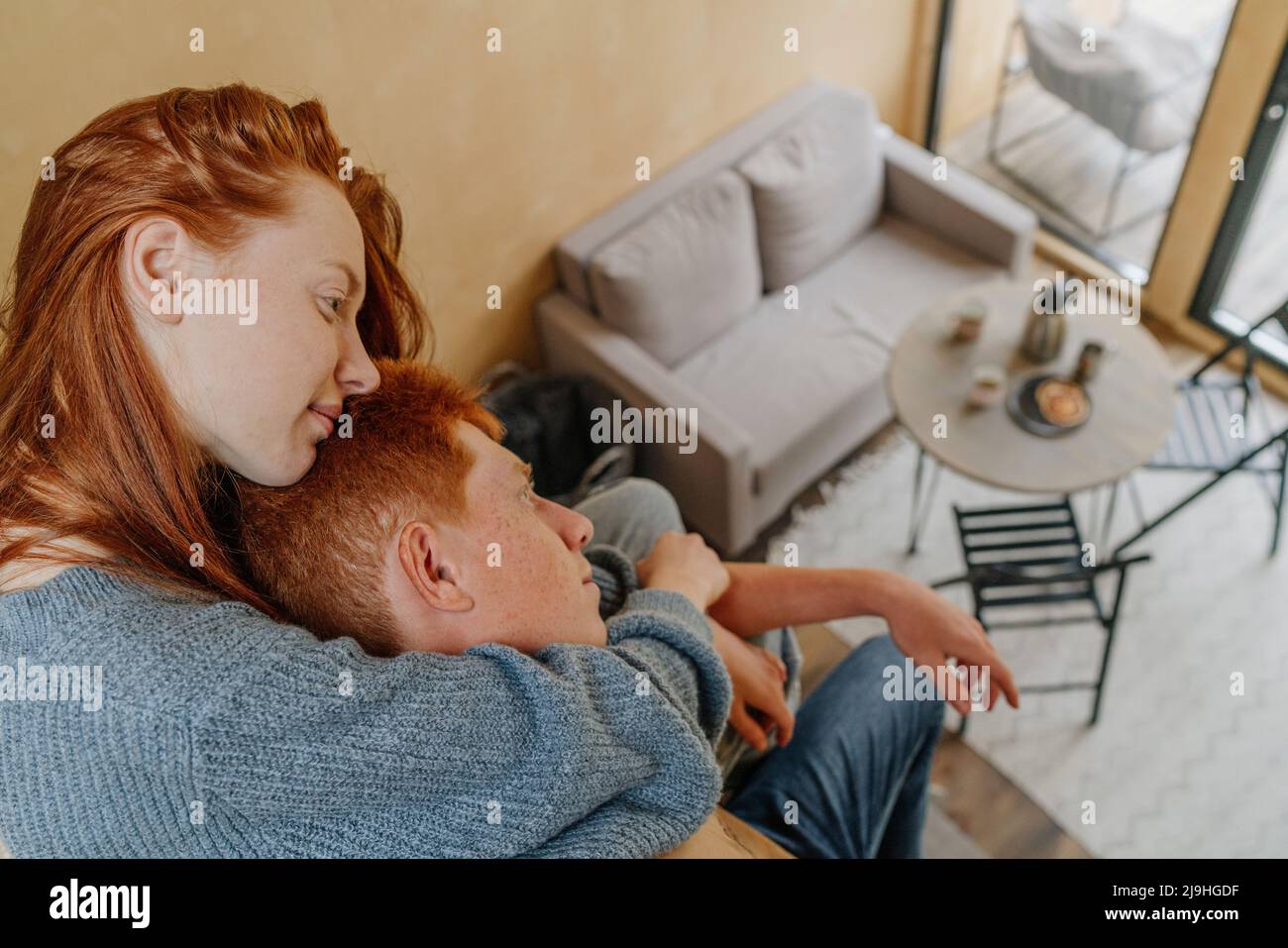 Young woman embracing boyfriend from back sitting in living room Stock ...