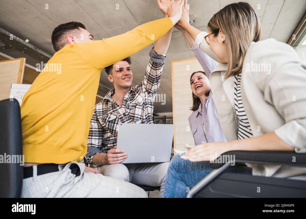 Happy business people high fiving in office Stock Photo - Alamy