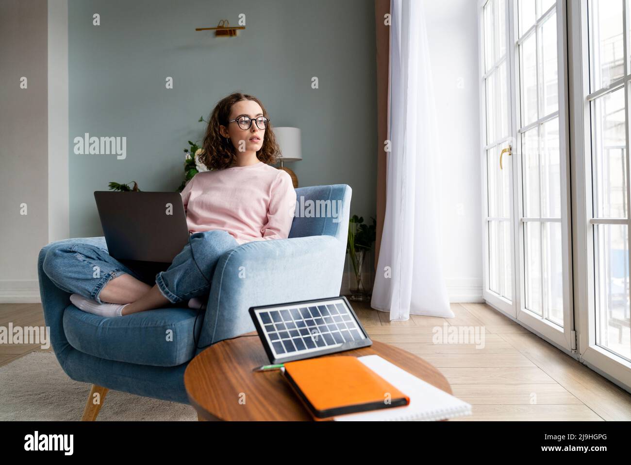 Young freelancer with laptop sitting at home Stock Photo - Alamy