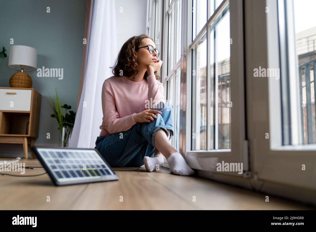 Contemplative freelancer looking through window in living room Stock ...