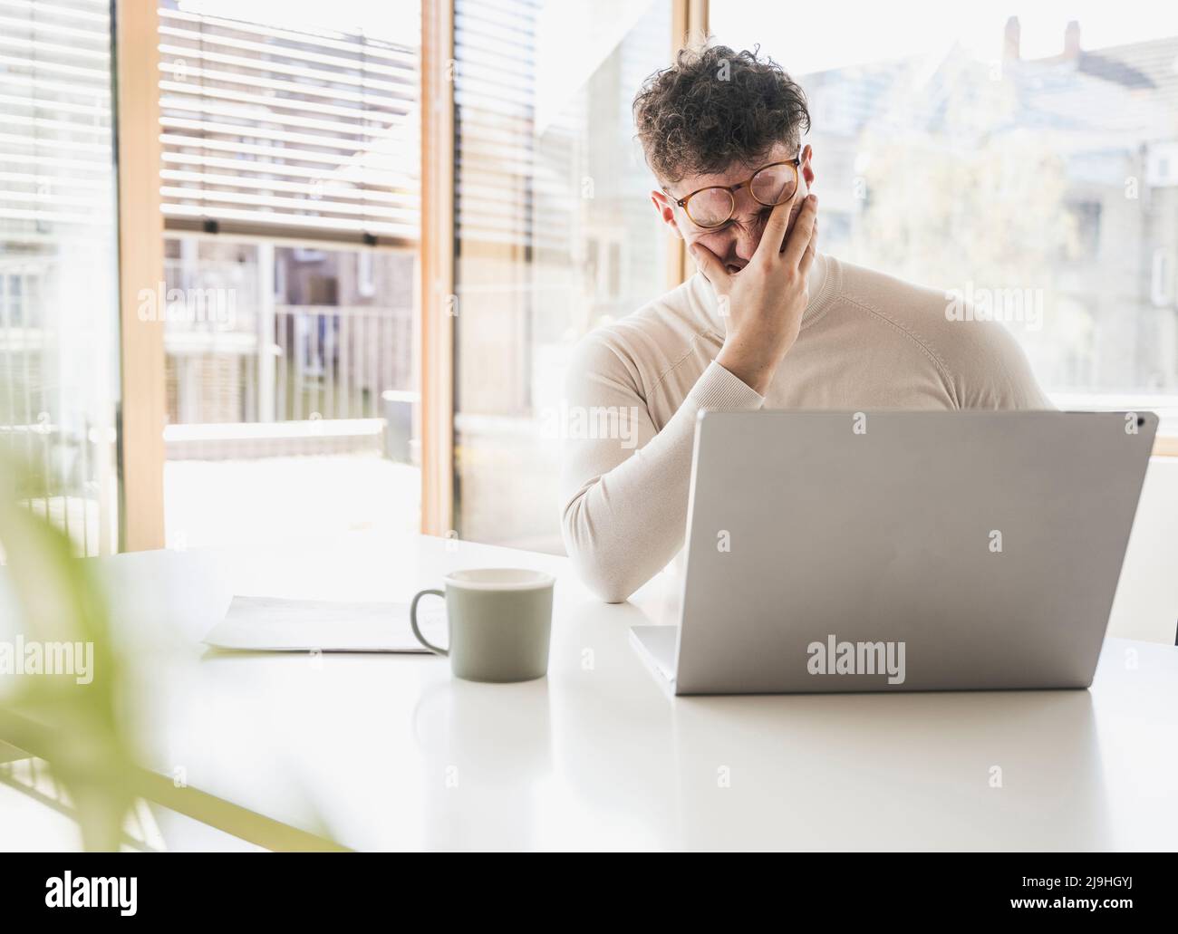 Stressed young businessman rubbing eyes at desk in office Stock Photo ...