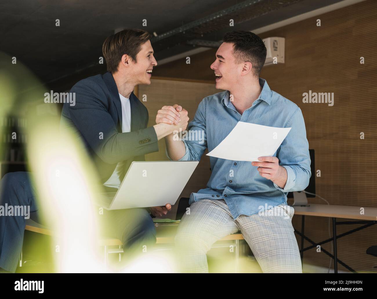 Two happy colleagues shaking hands in office Stock Photo - Alamy