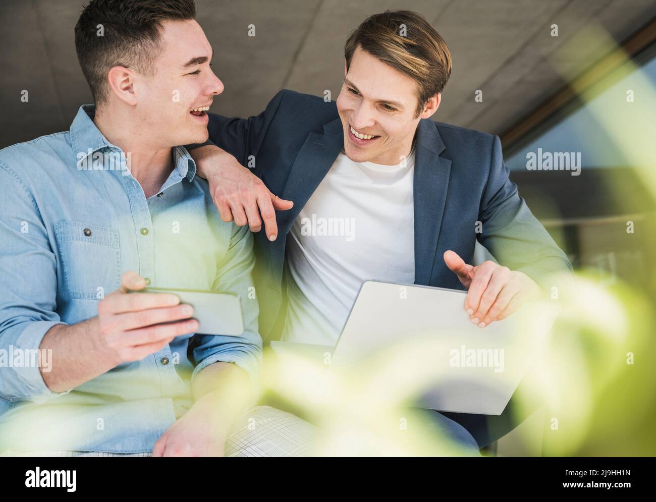 Two happy colleagues sharing smartphone in office Stock Photo - Alamy