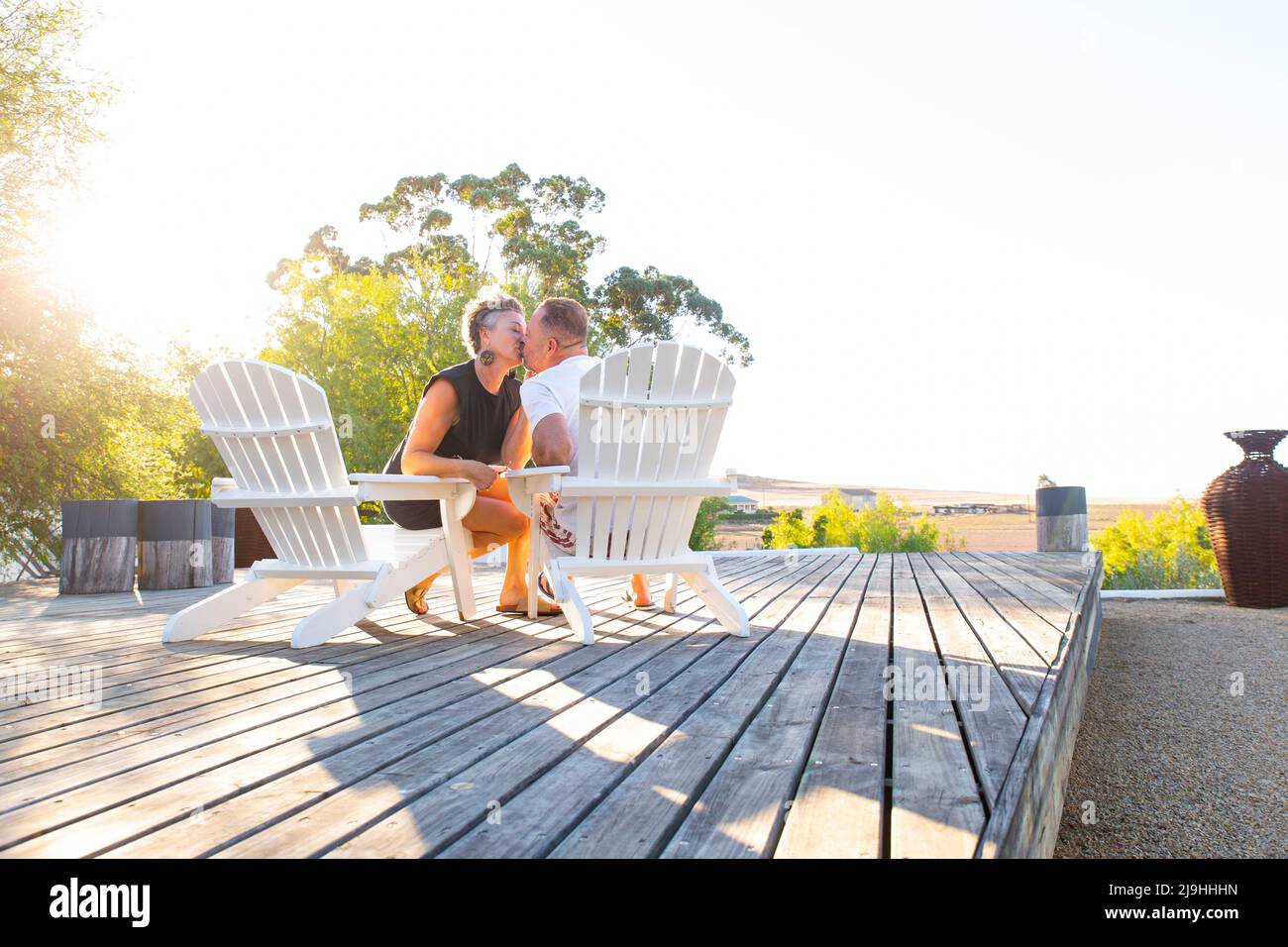 Couple kissing each other sitting on chair at patio Stock Photo - Alamy