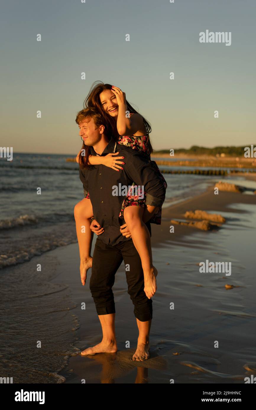 Young man giving piggyback ride to woman at beach on sunset Stock Photo ...