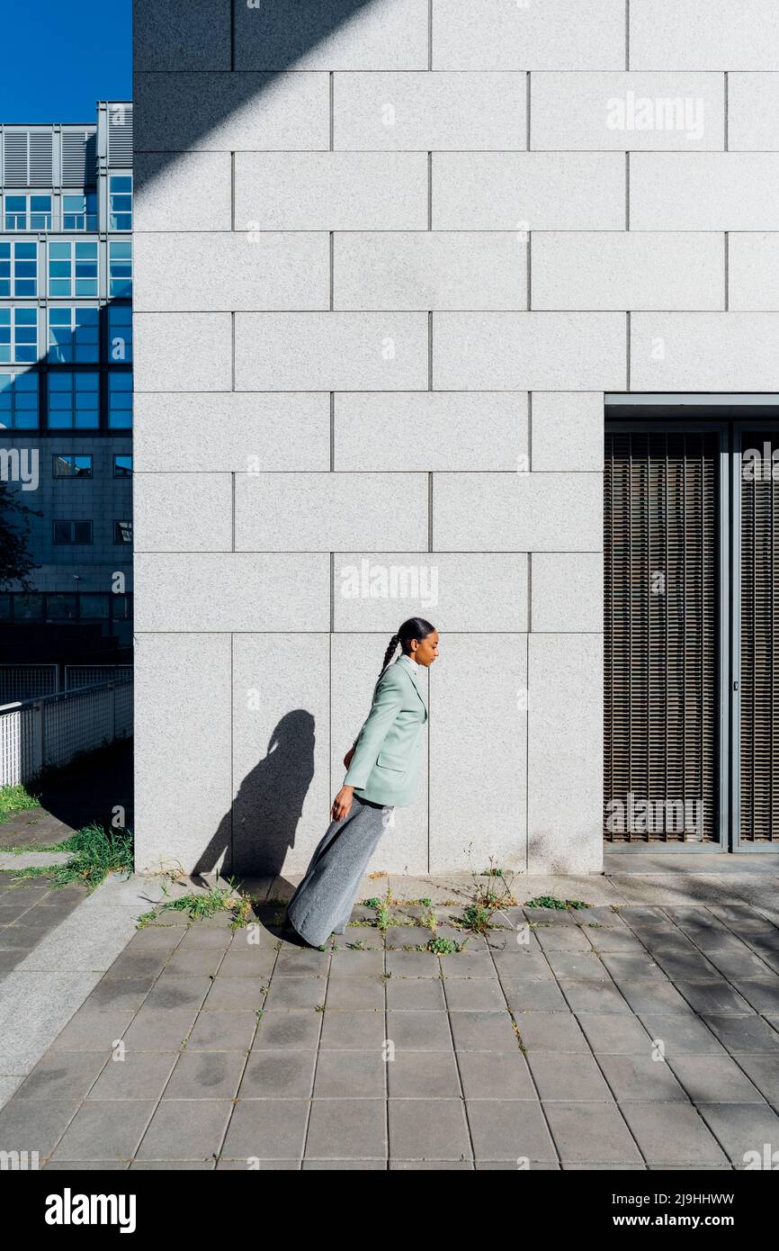 Young businesswoman in slanting position office building on sunny day ...