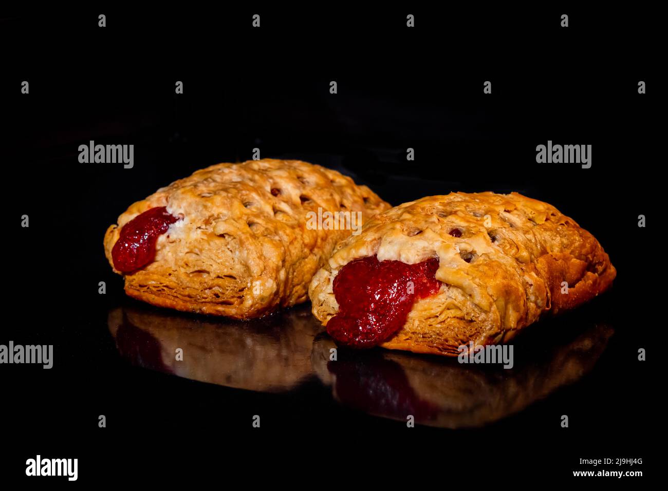 Two baked homemade buns with red strawberry jam, black background Stock ...