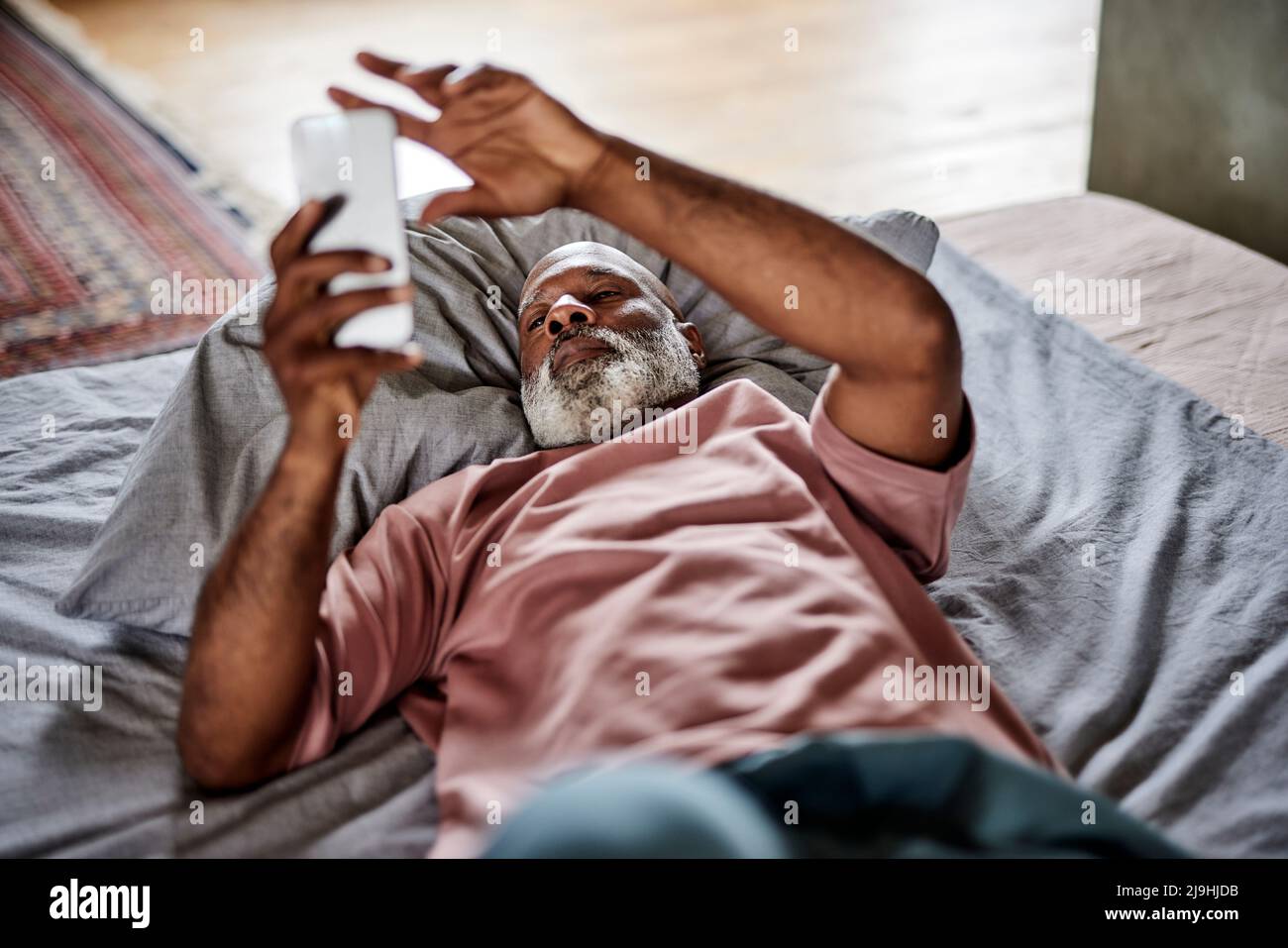 Man using mobile phone lying on bed at home Stock Photo - Alamy