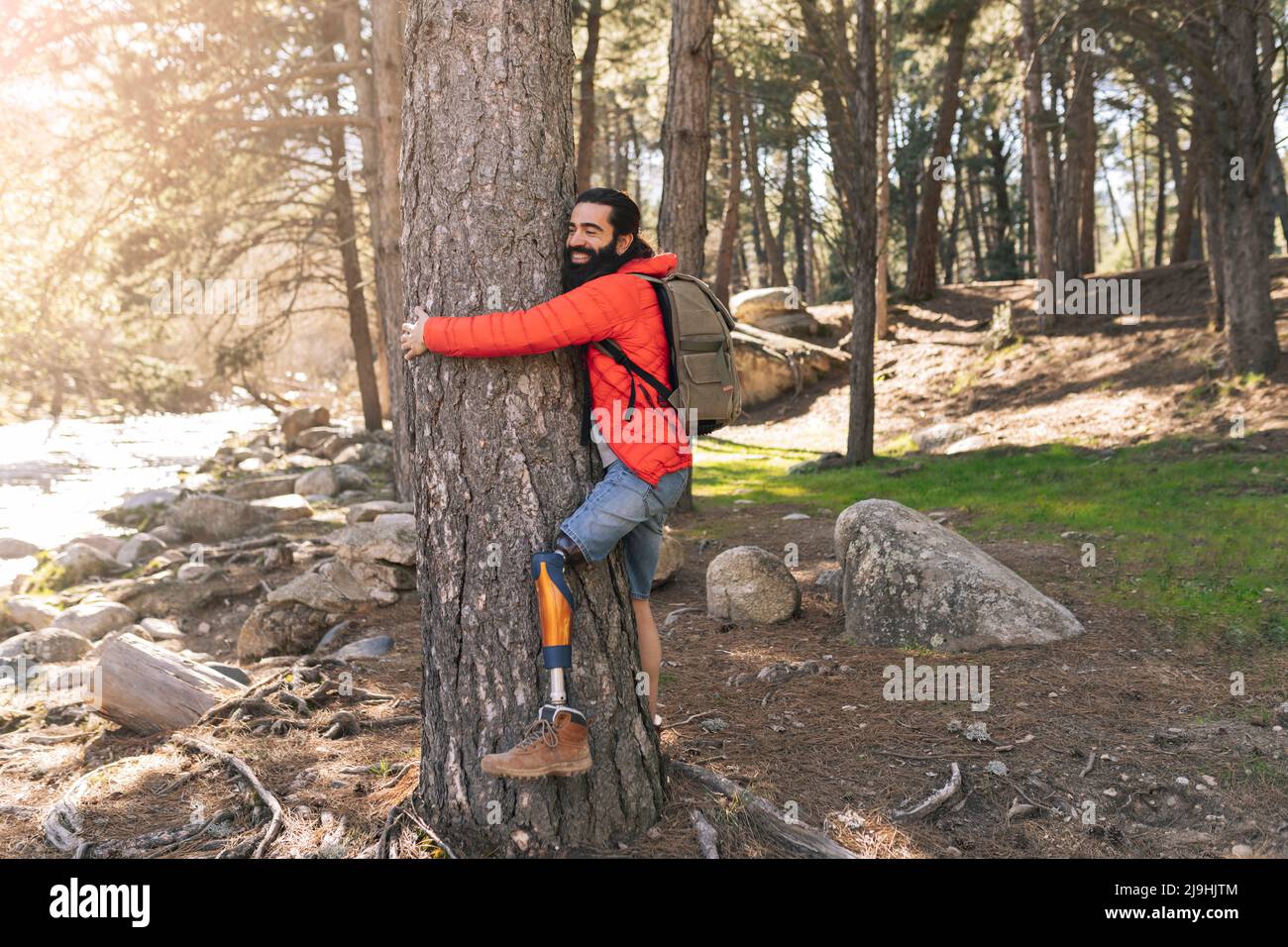 Happy disabled man hugging tree in forest Stock Photo - Alamy