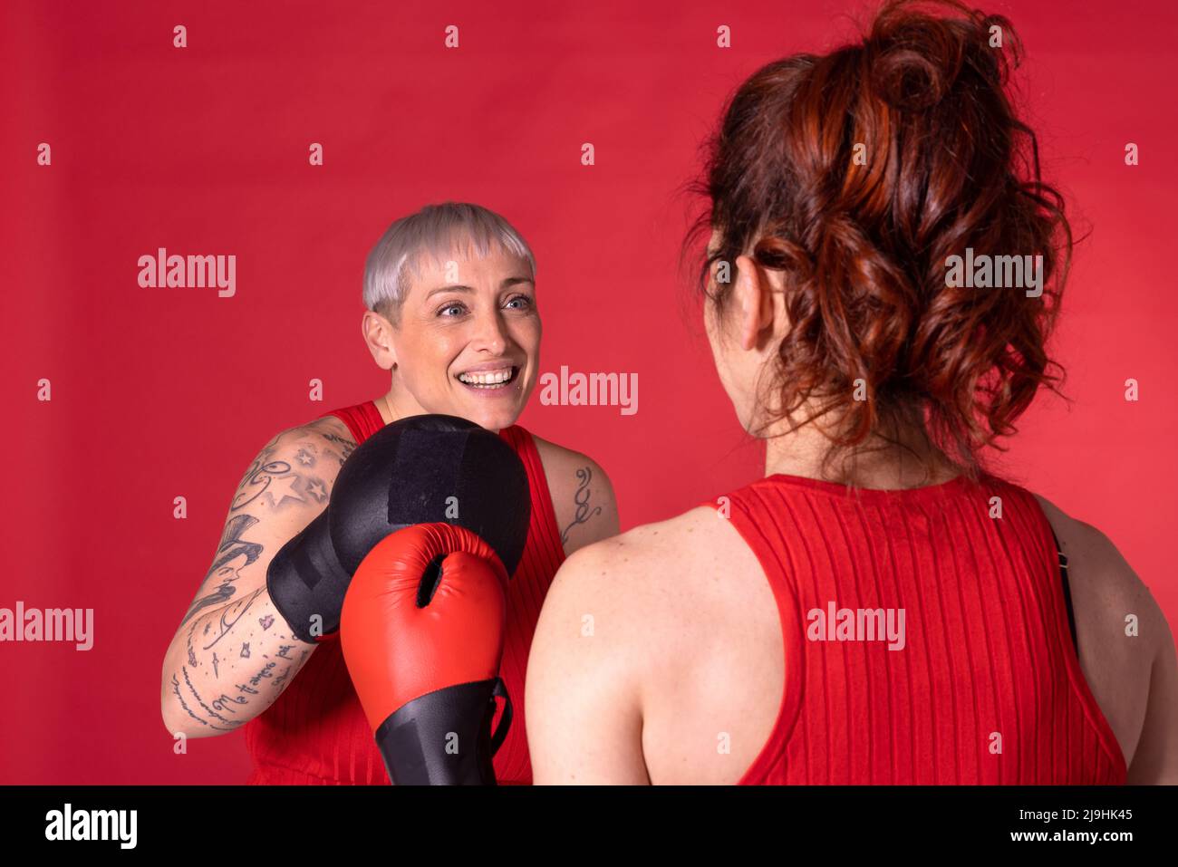 Happy woman boxing with friend against red background Stock Photo - Alamy