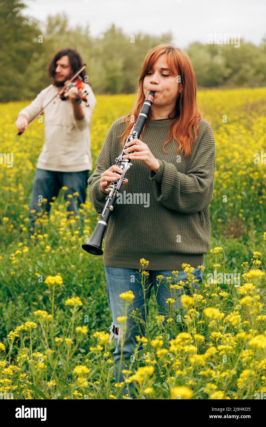 Man and woman practicing musical instruments in flower field Stock ...