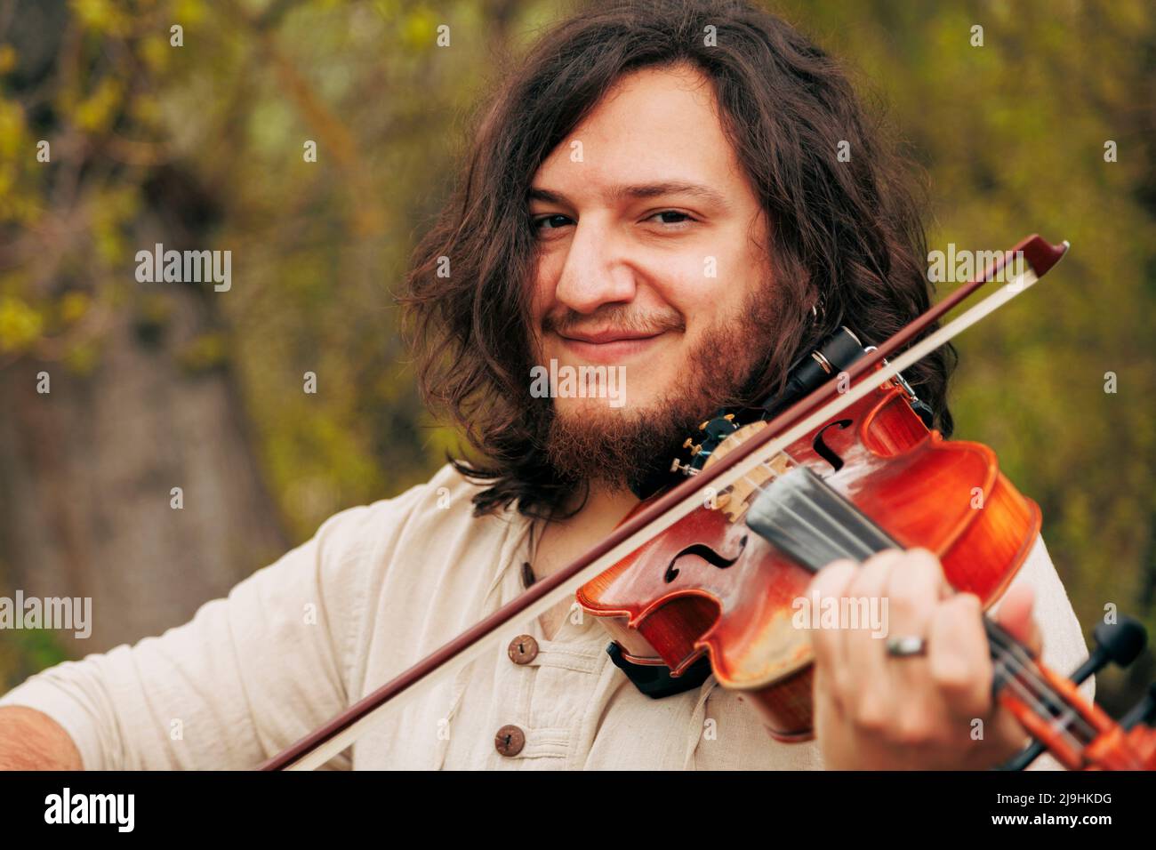 Smiling man with long hair playing violin Stock Photo - Alamy