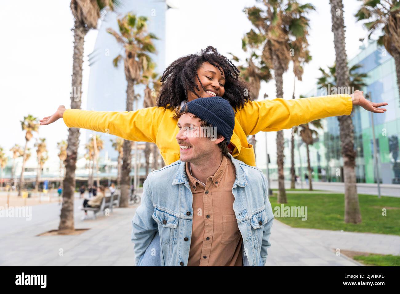Smiling woman enjoying piggyback ride with man Stock Photo - Alamy