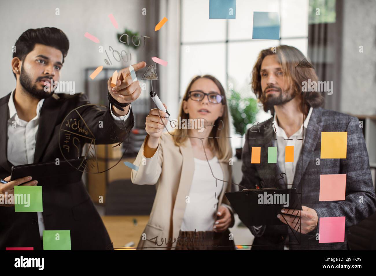 Multicultural team noting new information on clipboard and tablet ...