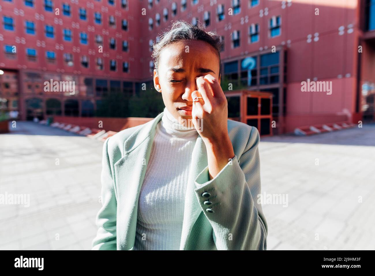 Young businesswoman wiping tears in front of office building Stock ...