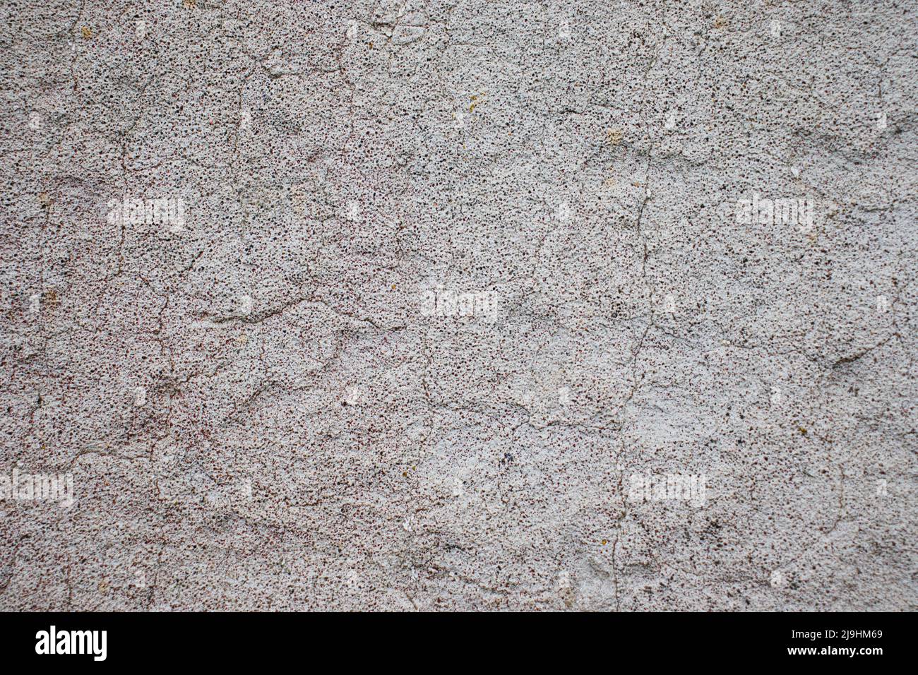 An old concrete wall with remnants of gray paint crumbling from time ...