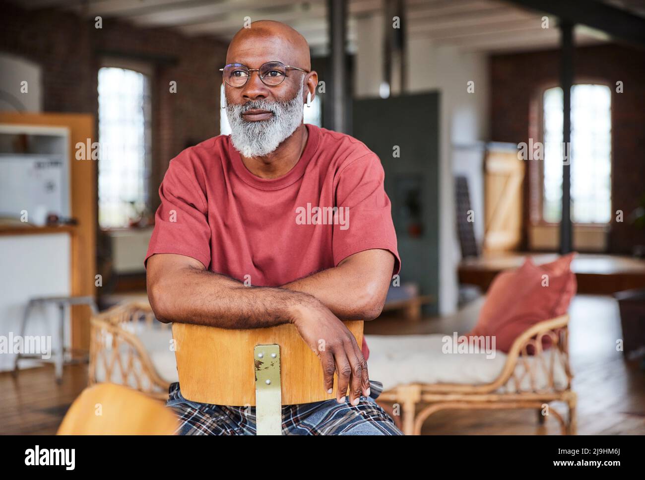 Contemplative man with eyeglasses sitting on chair at home Stock Photo ...