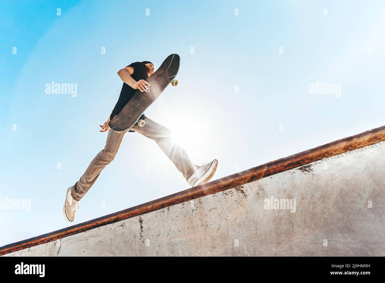 Man with skateboard running at skateboard park on sunny day Stock Photo ...