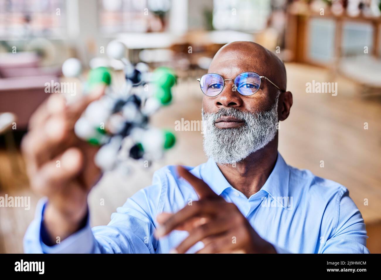 Mature scientist pointing at molecular model at home Stock Photo - Alamy