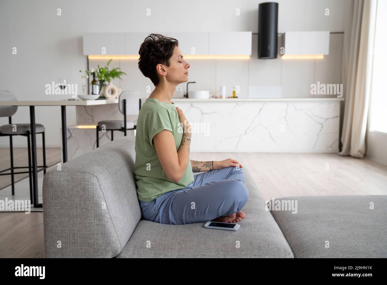 Woman doing relaxation exercise sitting on sofa at home Stock Photo - Alamy