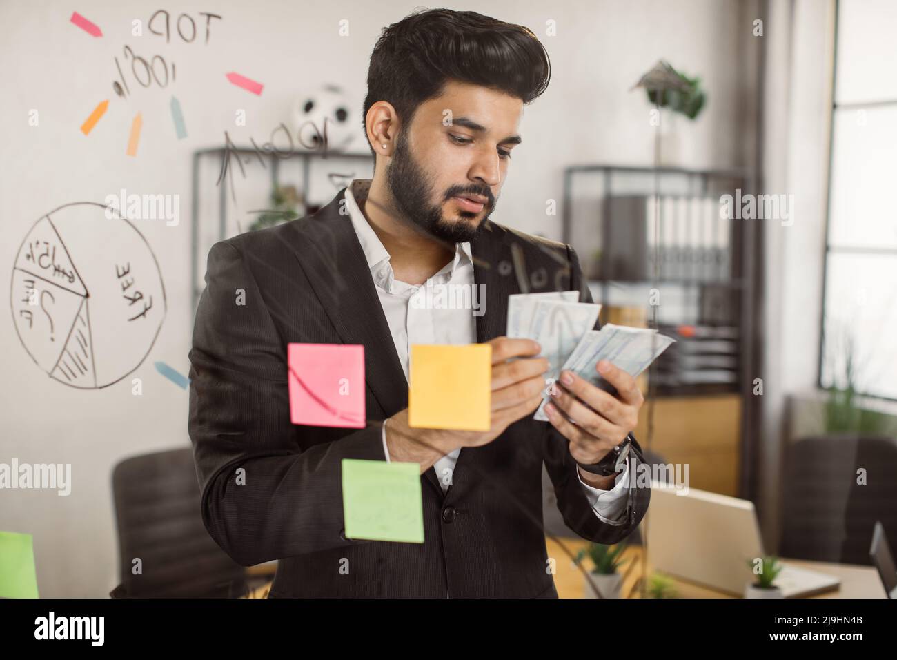 Concentrated male chief in formal clothes counting money while standing ...
