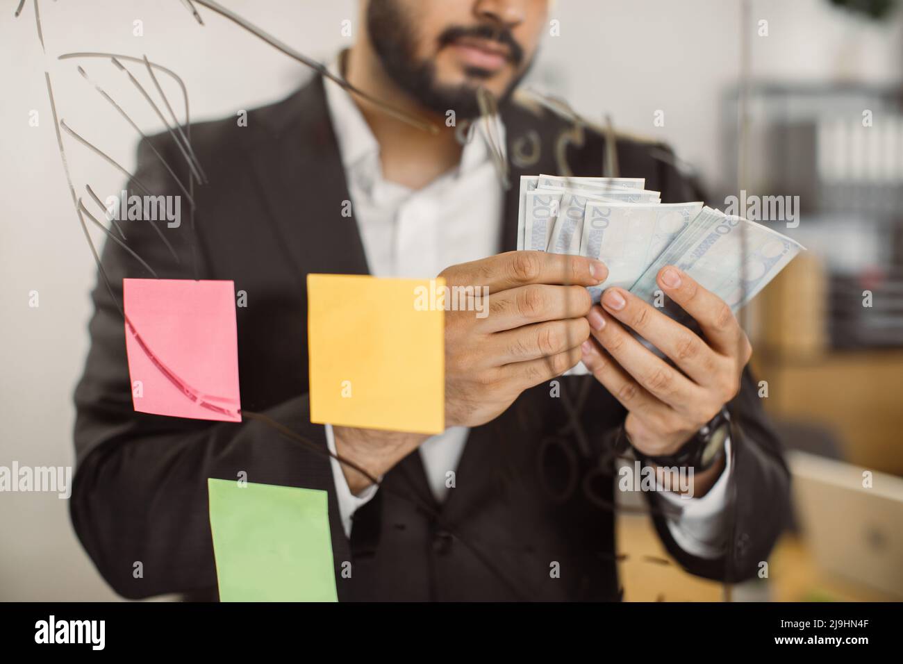 Loose up of concentrated male chief in formal clothes counting money ...