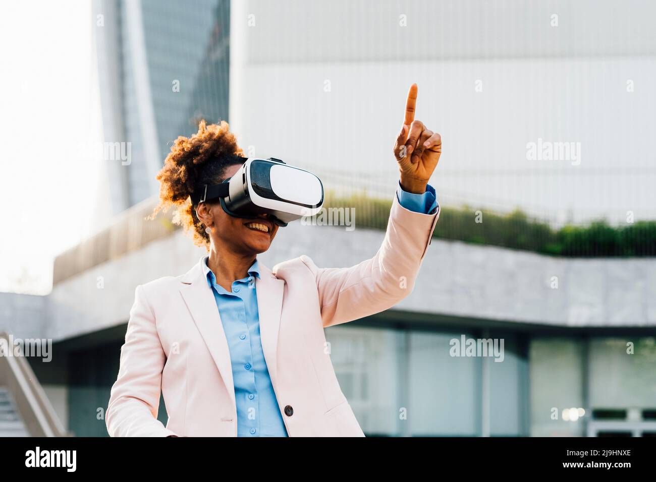 Happy businesswoman wearing virtual reality simulator gesturing in ...