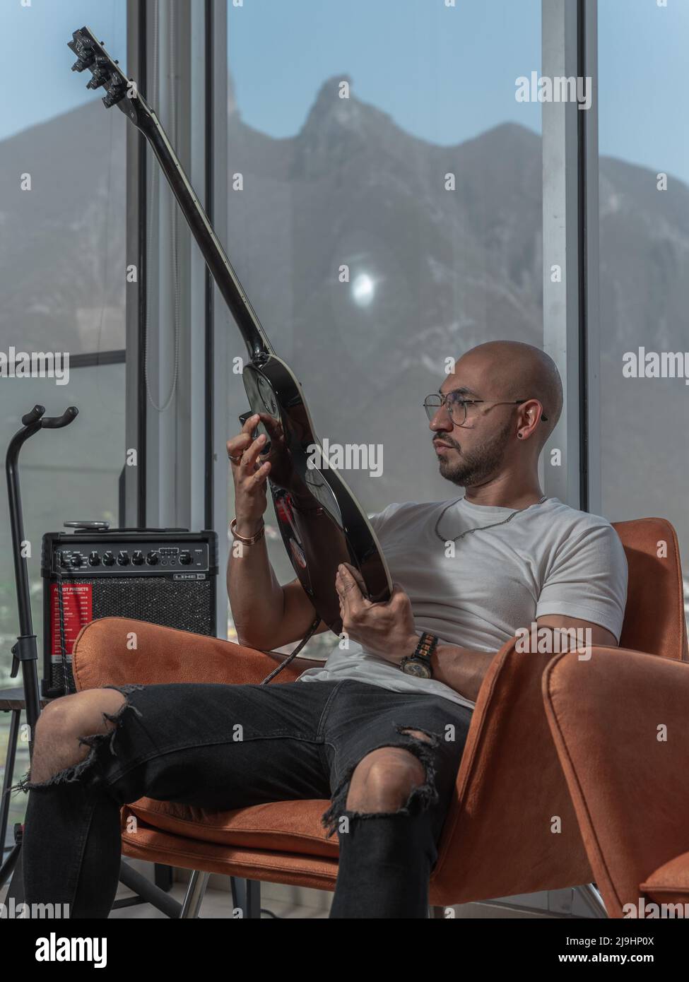 young bald man plays his guitar and admires it on his couch Stock Photo ...