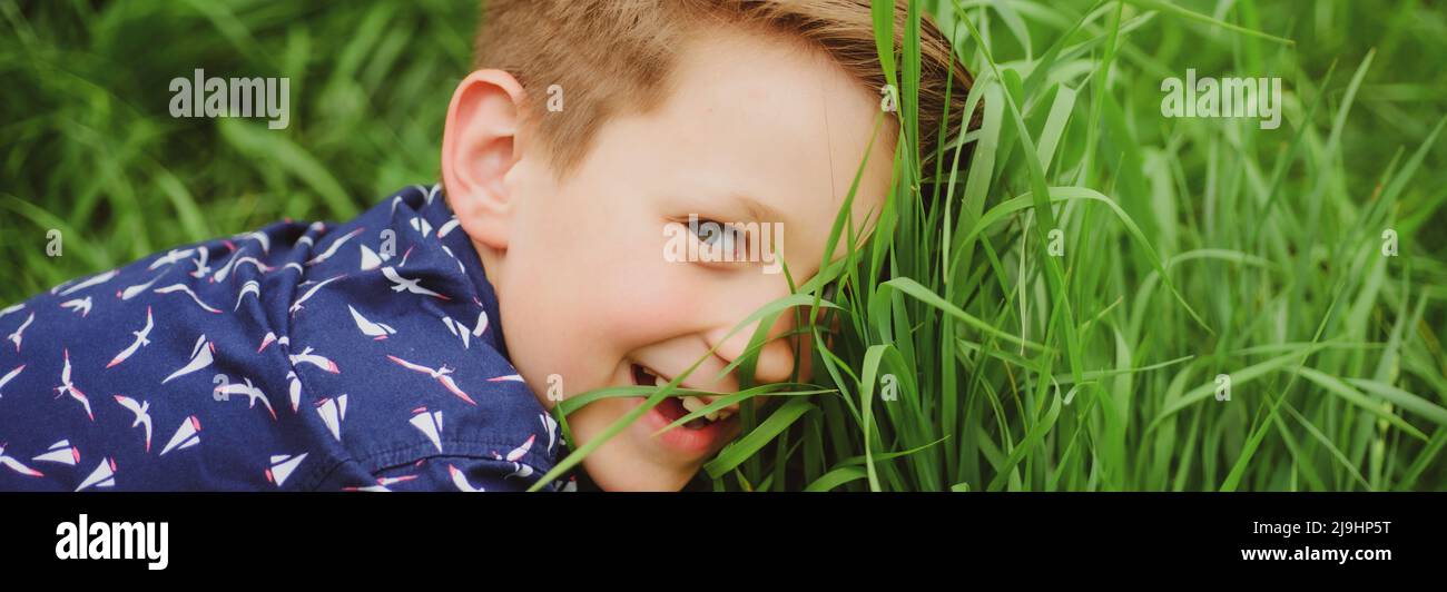 Banner with spring child face. Smiling child boy with grass background ...