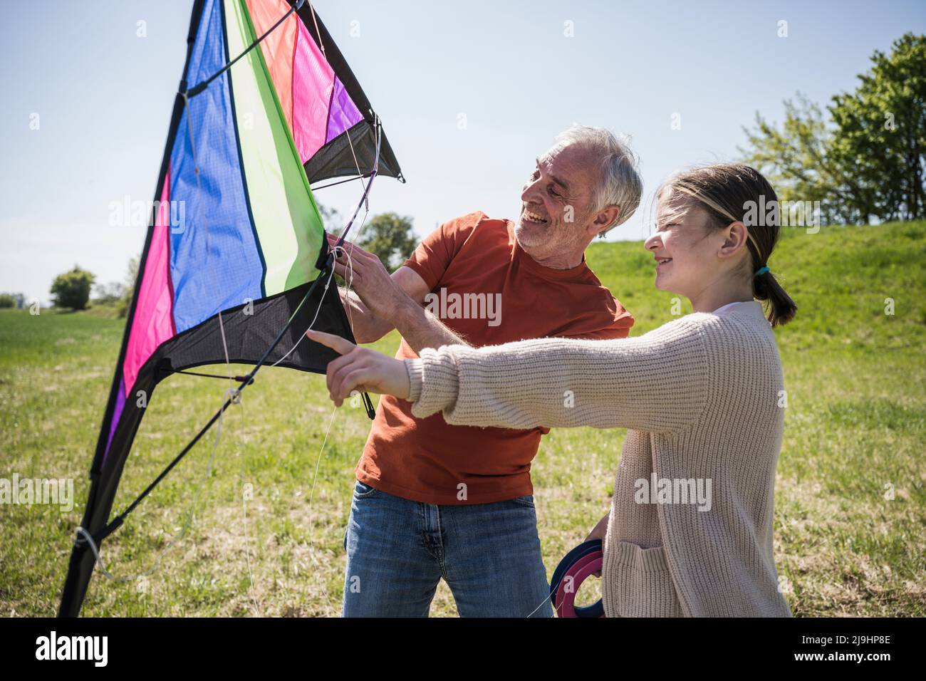 Grandfather guiding granddaughter to fly kite on field Stock Photo - Alamy