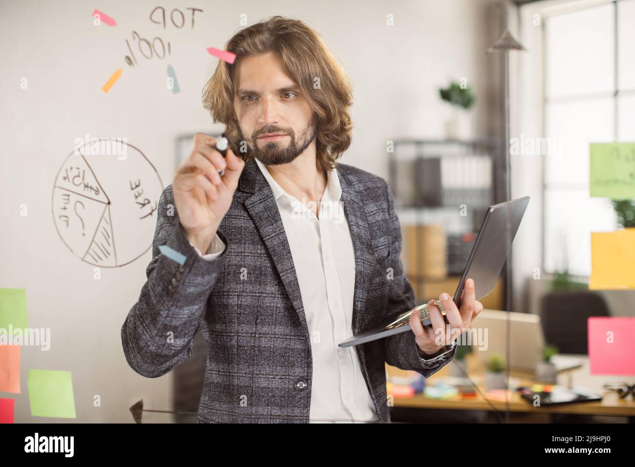 Male office employee with stylish haircut holding modern laptop and ...